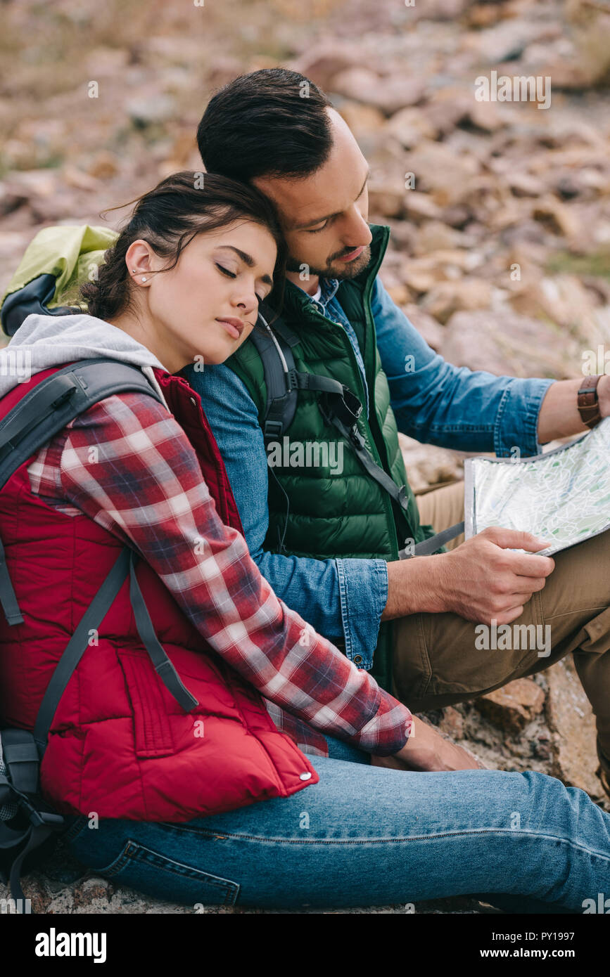 side view of hikers with backpacks and map resting on rocks Stock Photo ...