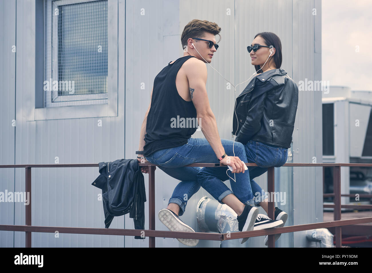 beautiful multicultural couple listening music with earphones while ...