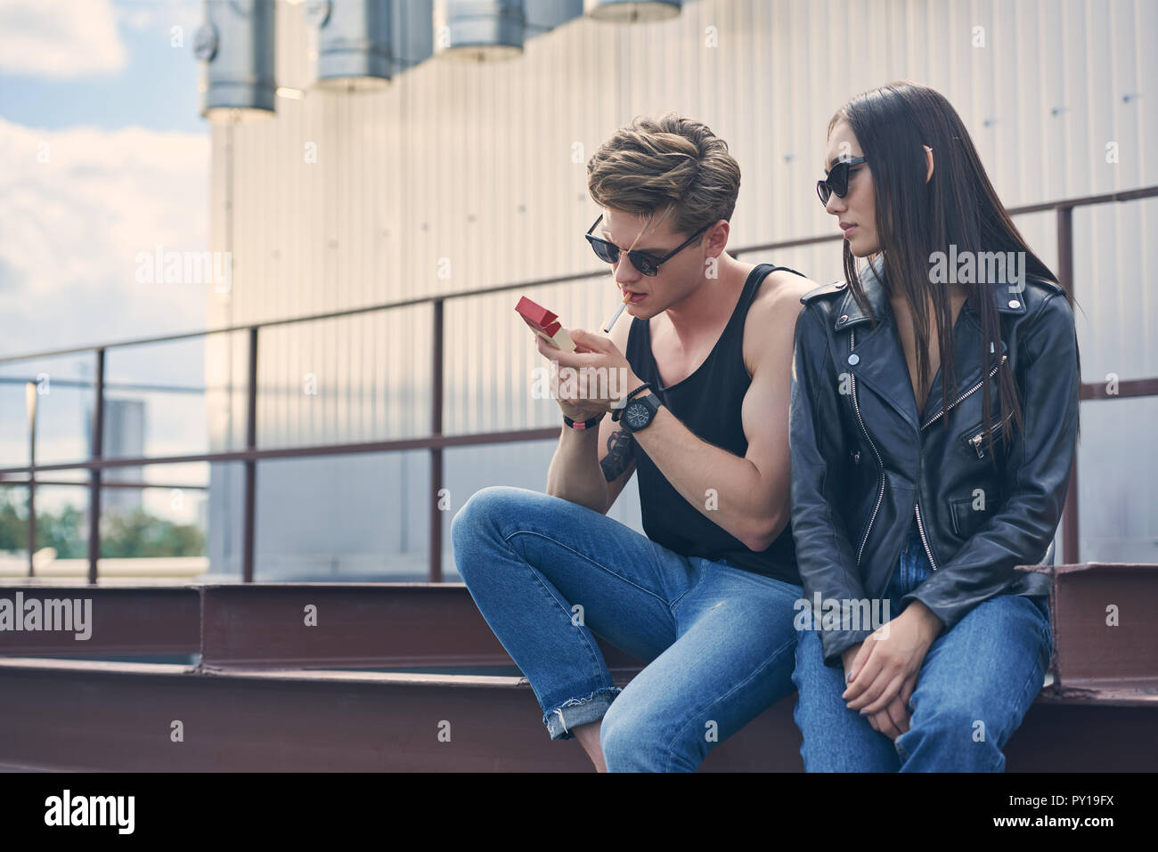young stylish man smoking cigarette near his asian girlfriend Stock ...