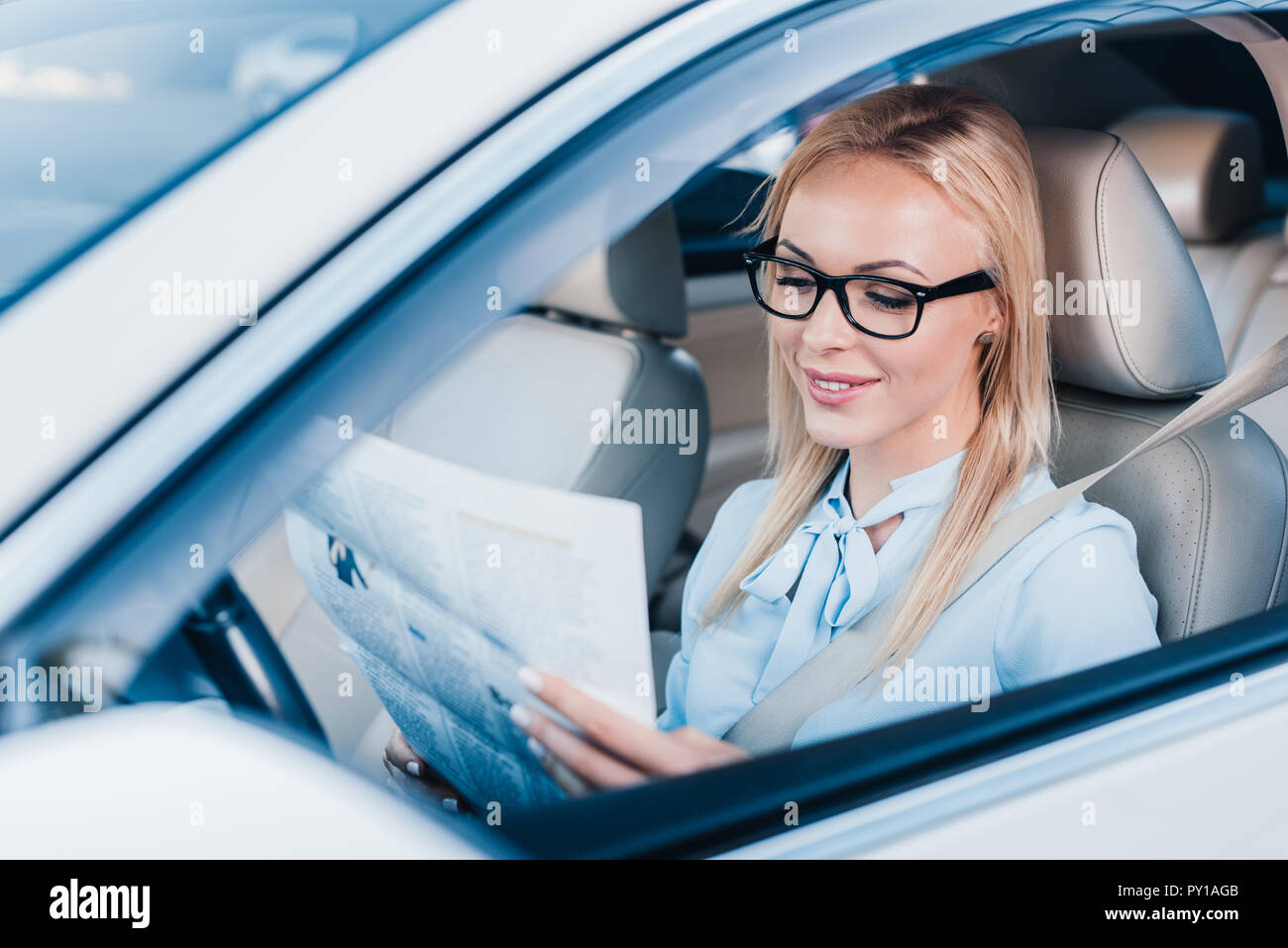 smiling businesswoman reading newspaper in car Stock Photo - Alamy