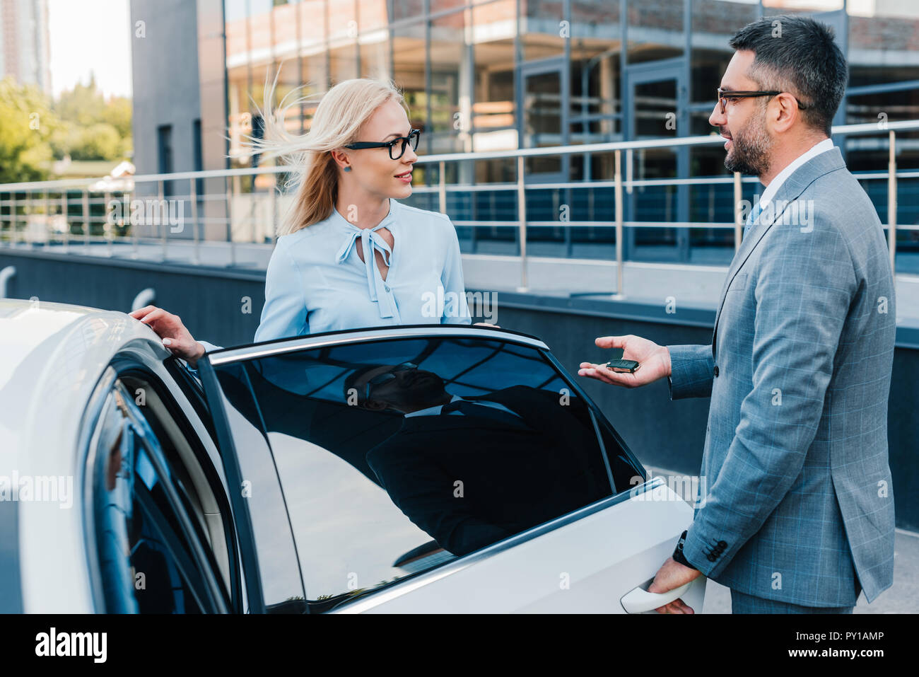 side view of business colleagues having conversation near car on street ...