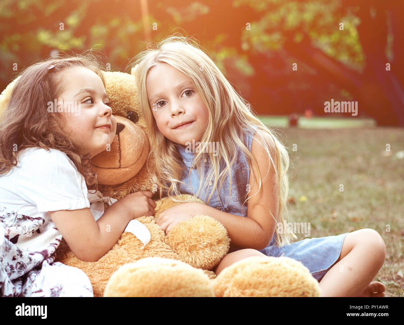 Two cute girls hugging a huge, new teddy bear Stock Photo - Alamy