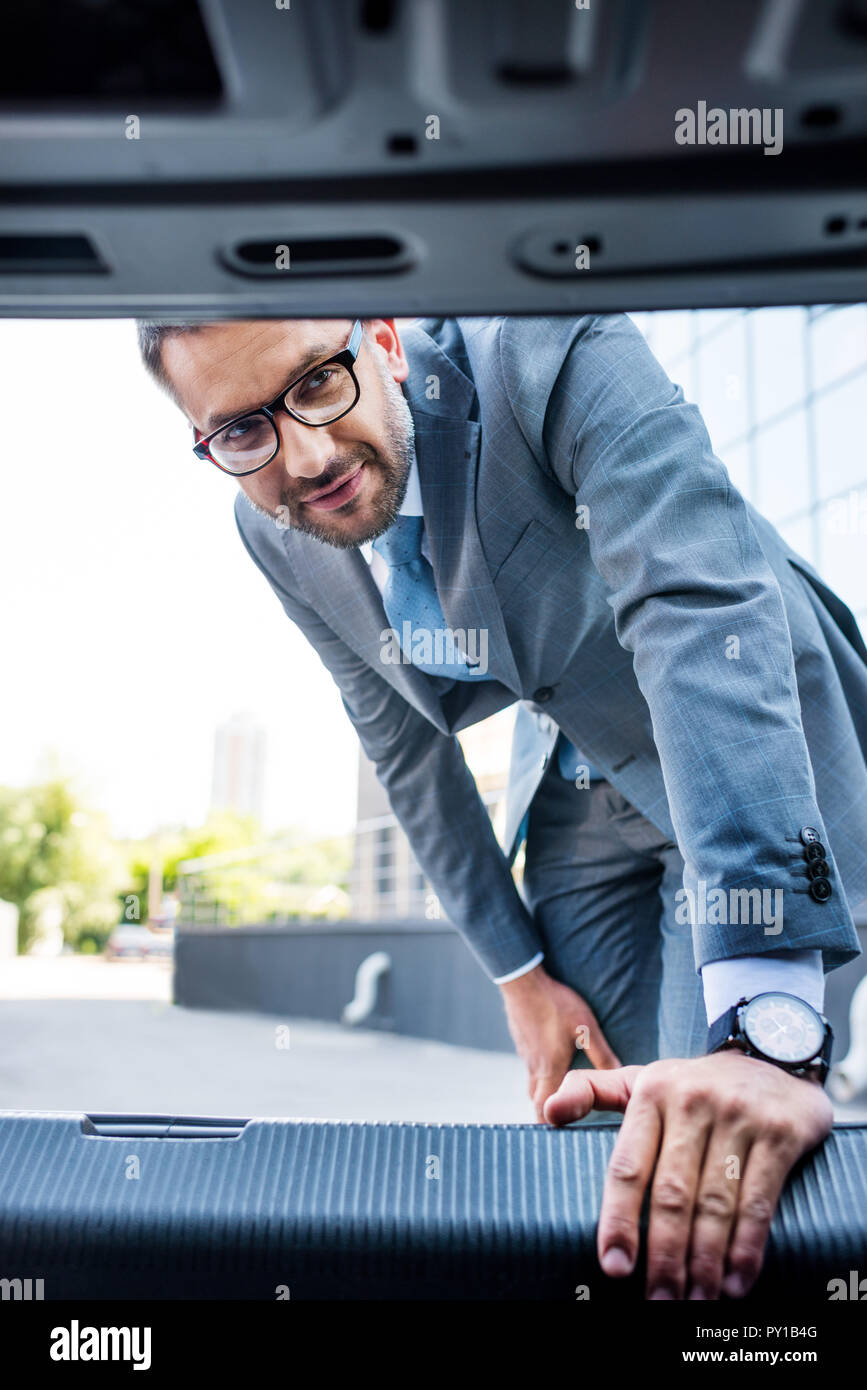 businessman in suit and eyeglasses looking into car luggage boot Stock ...