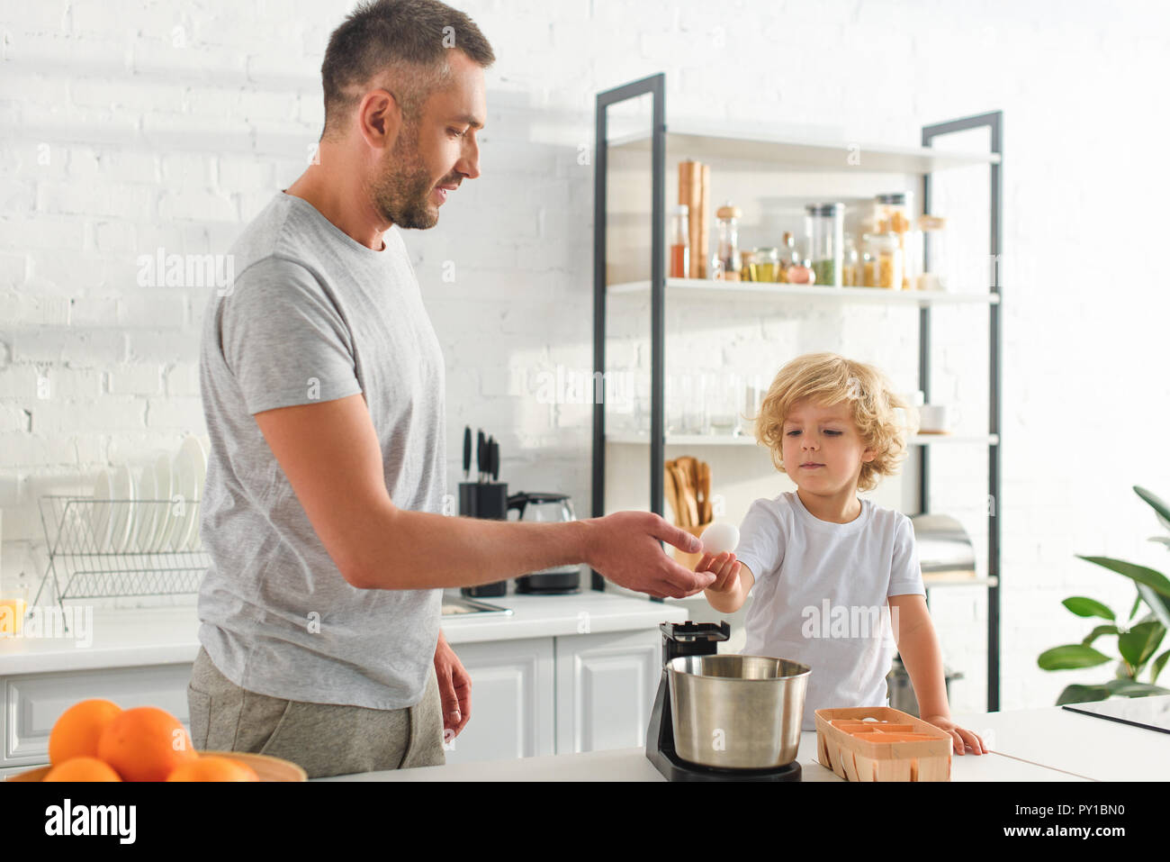 boy giving egg to father near tabletop at kitchen Stock Photo - Alamy