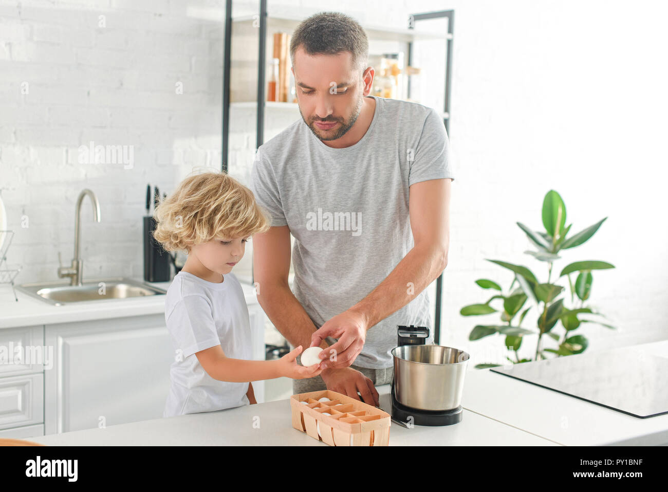 father giving egg to little son near tabletop at kitchen Stock Photo ...