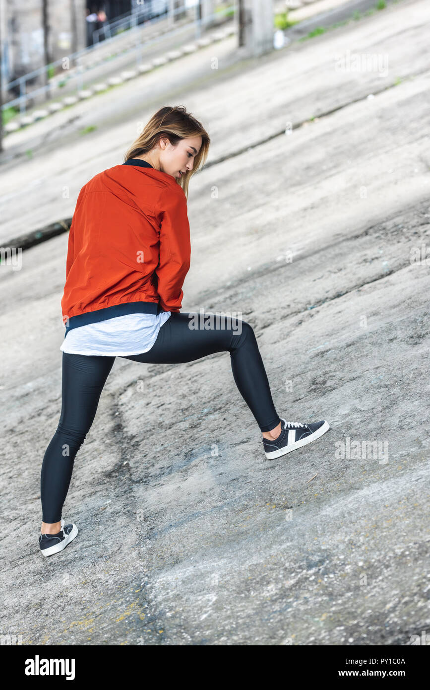 side view of young asian stylish female urban dancer dancing at city ...