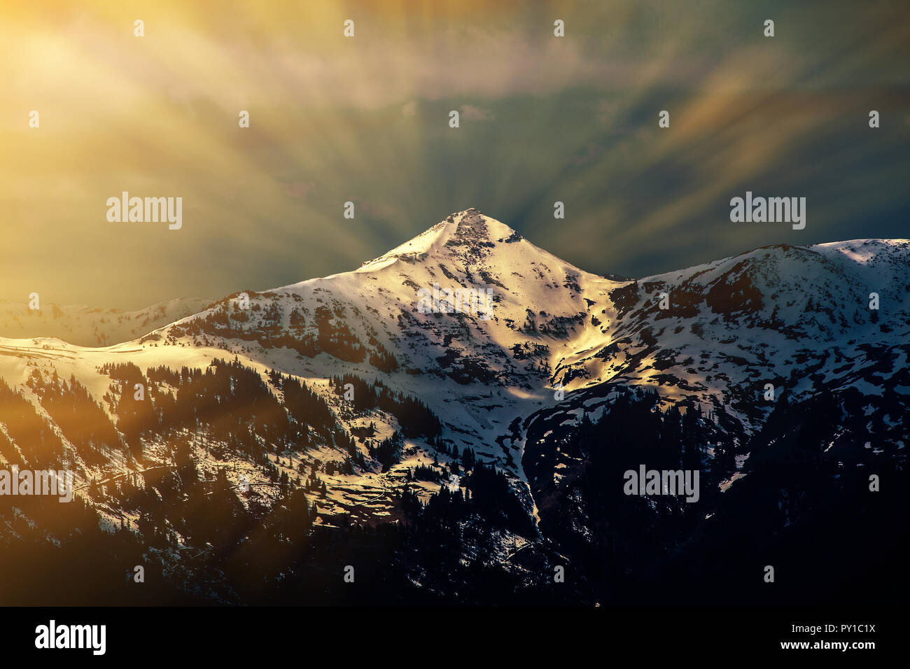 Glowing light behind winter mountain peak Stock Photo - Alamy