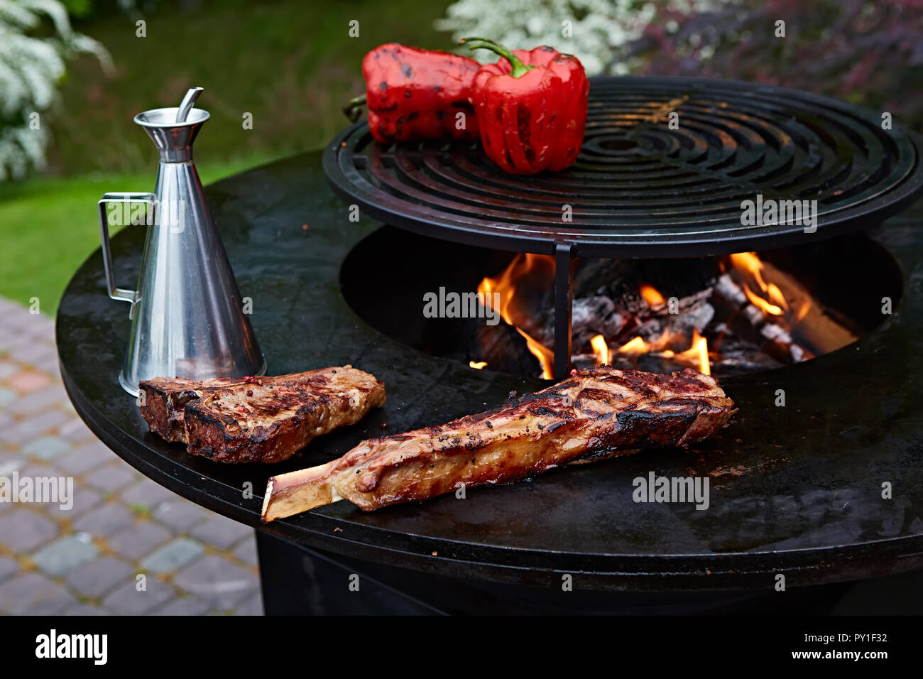 Tomahawk rib beef steak and T-bone on hot black grill Stock Photo - Alamy