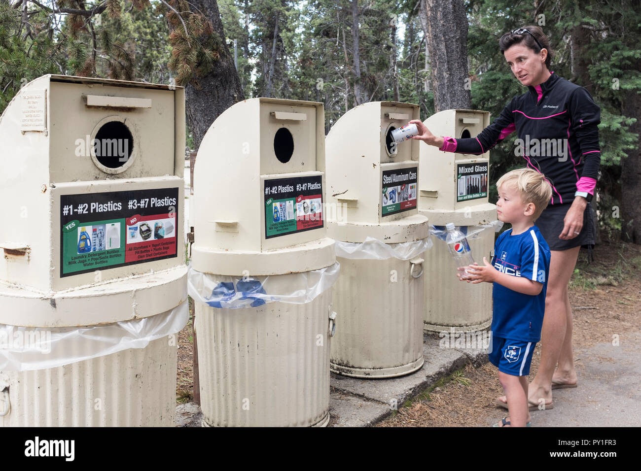 A young boy and his mother putting their trash into separate recylcling ...