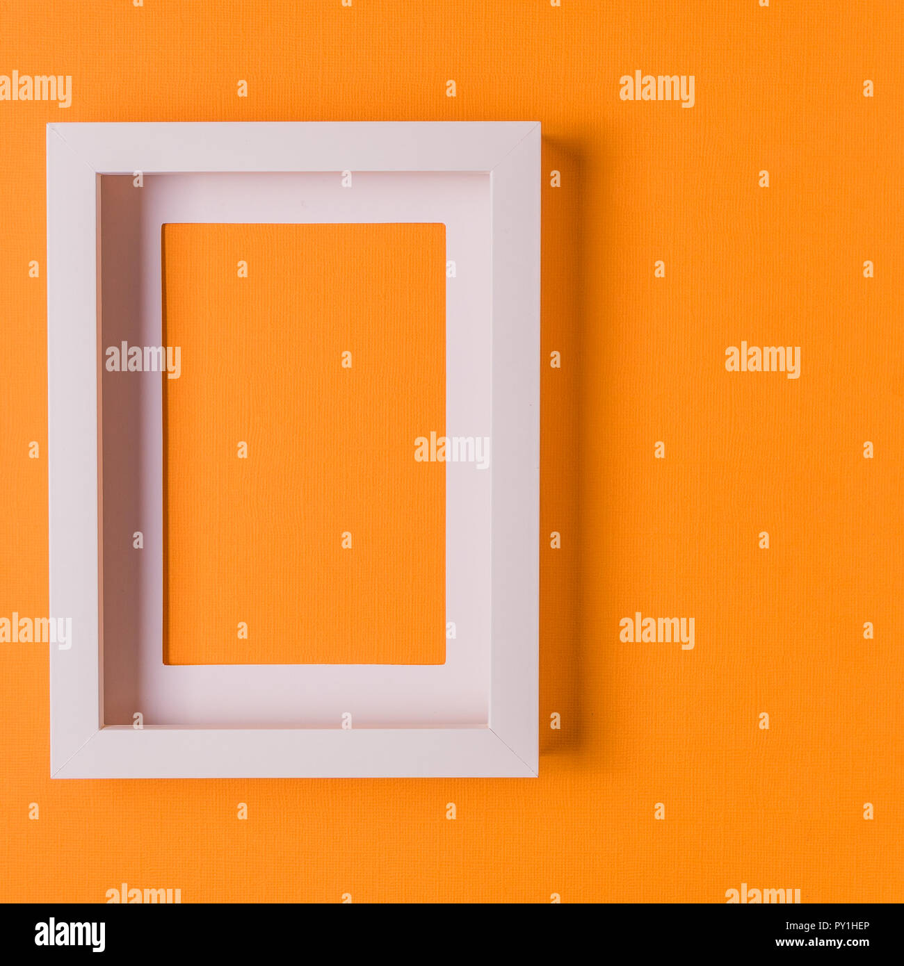 Minimalism style. White empty picture frame against orange paper ...