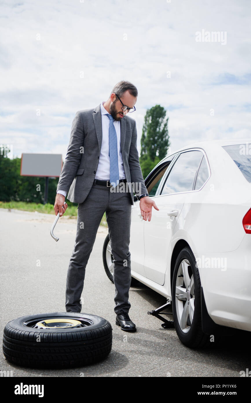 handsome man looking at broken car and tires on road Stock Photo - Alamy