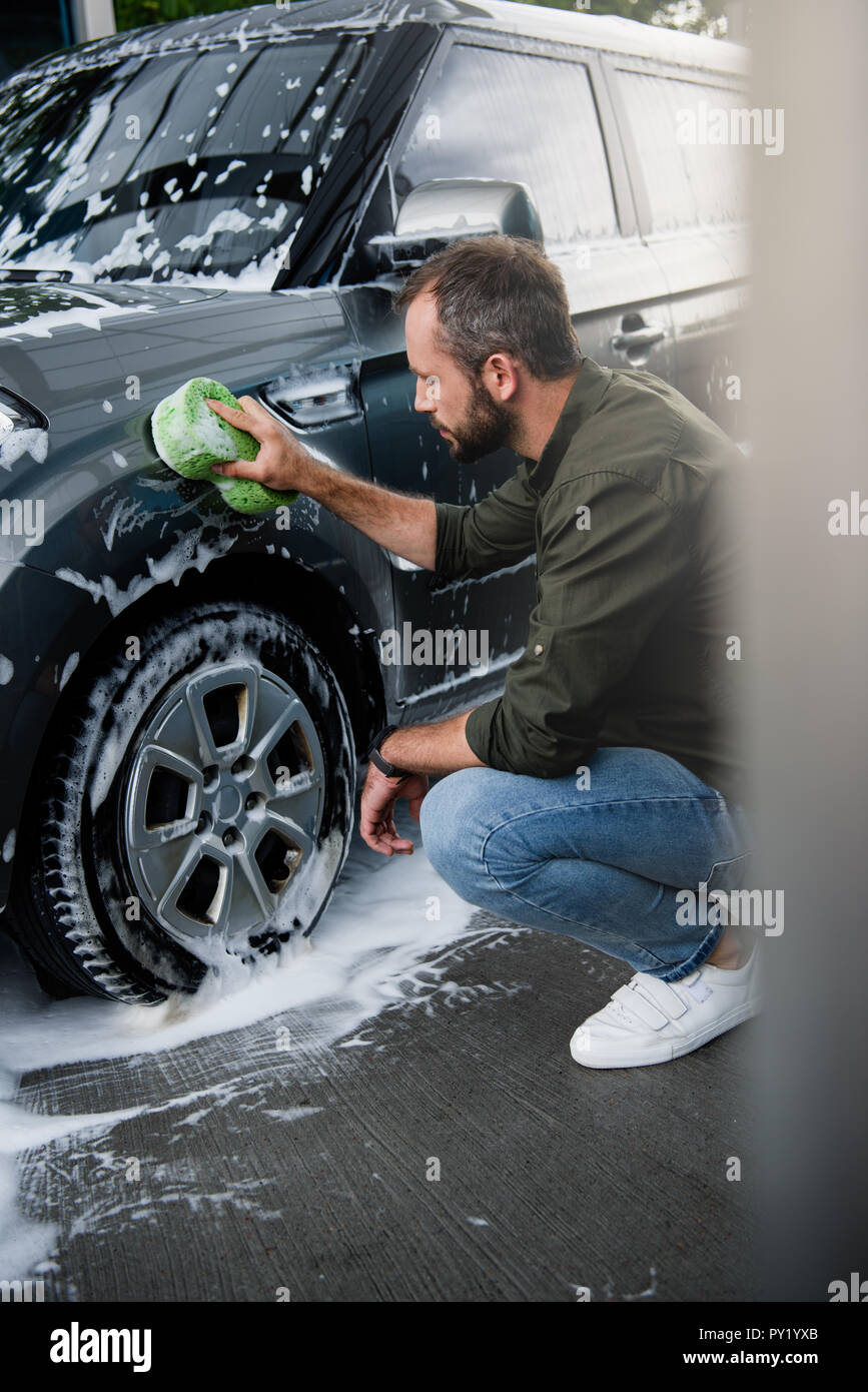 side view of handsome man cleaning car at car wash with rag Stock Photo ...