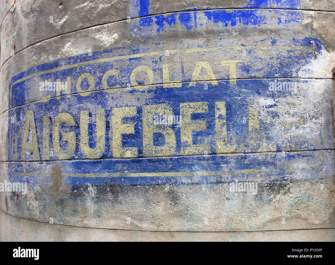Vintage, faded blue advertising poster on curved stone wall, Céret ...