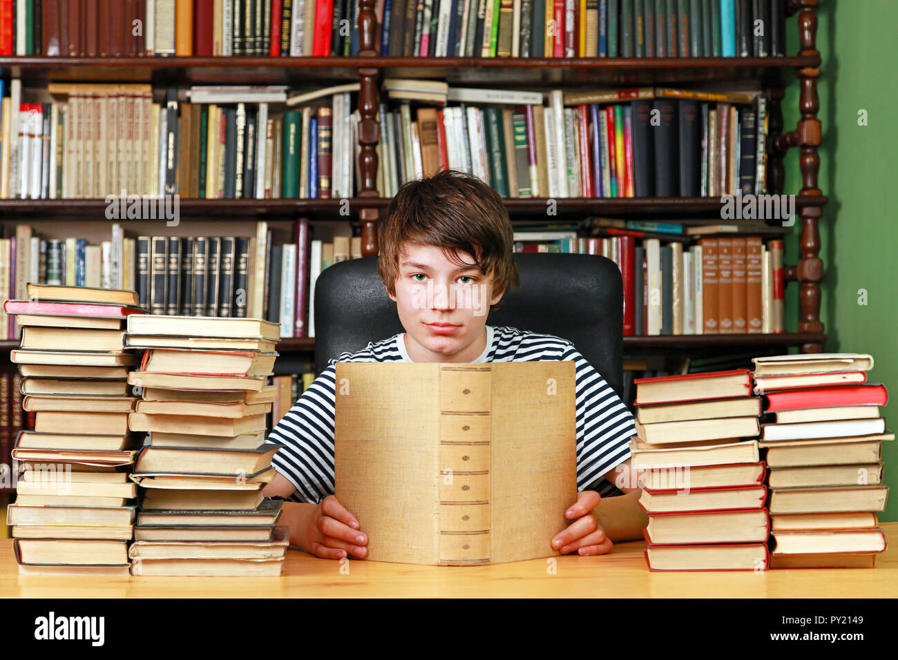 Young teenage boy reading in school library Stock Photo - Alamy