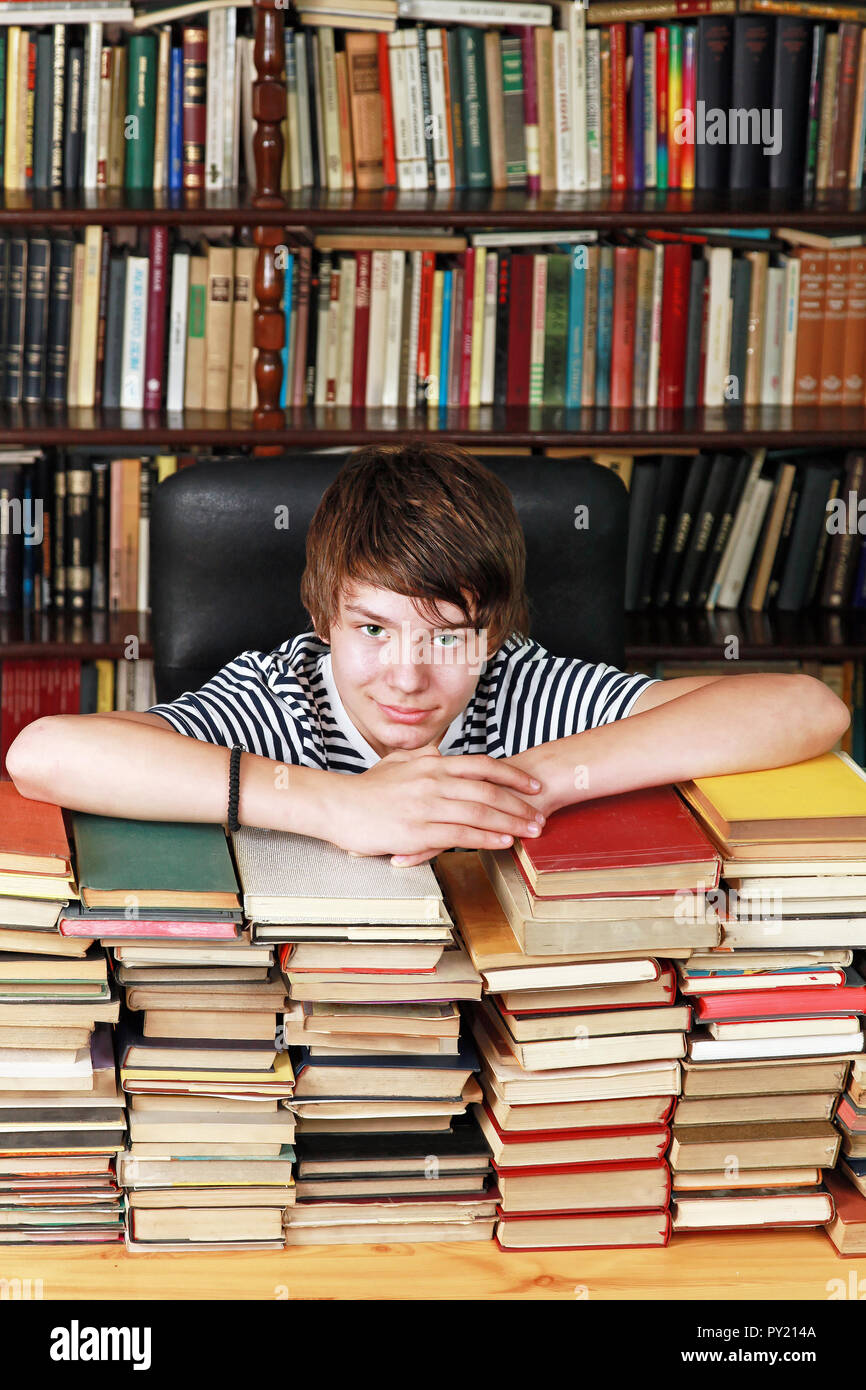 Young teenage boy with big pile of books in library Stock Photo - Alamy
