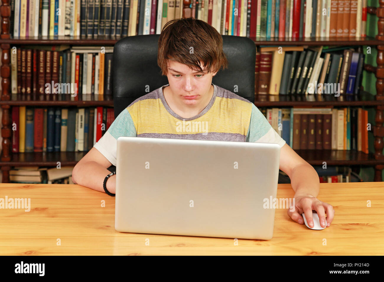 Teenage boy at desk with notebook computer in library Stock Photo - Alamy
