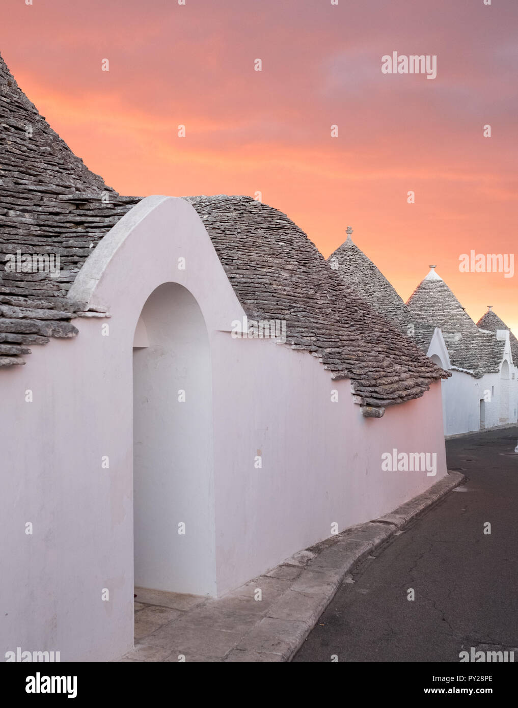 Traditional dry stone conical roofed trulli houses on street in Aia ...