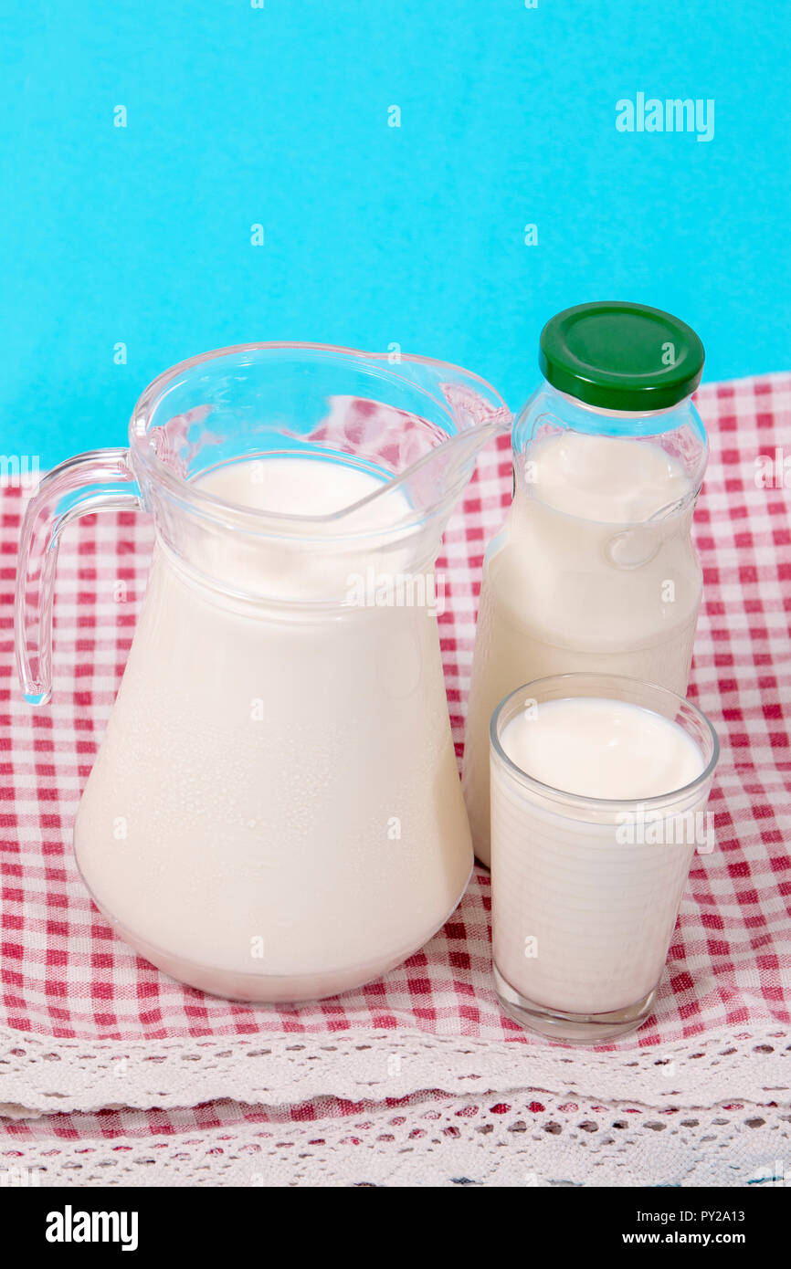 Mix of milk containers on a red table cloth isolated on a blue ...