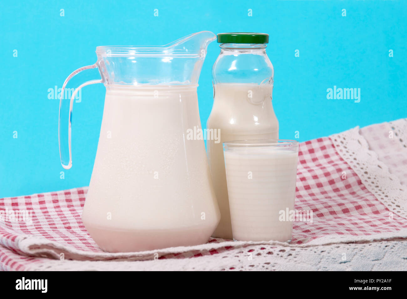 Mix of milk containers on a red table cloth isolated on a blue ...