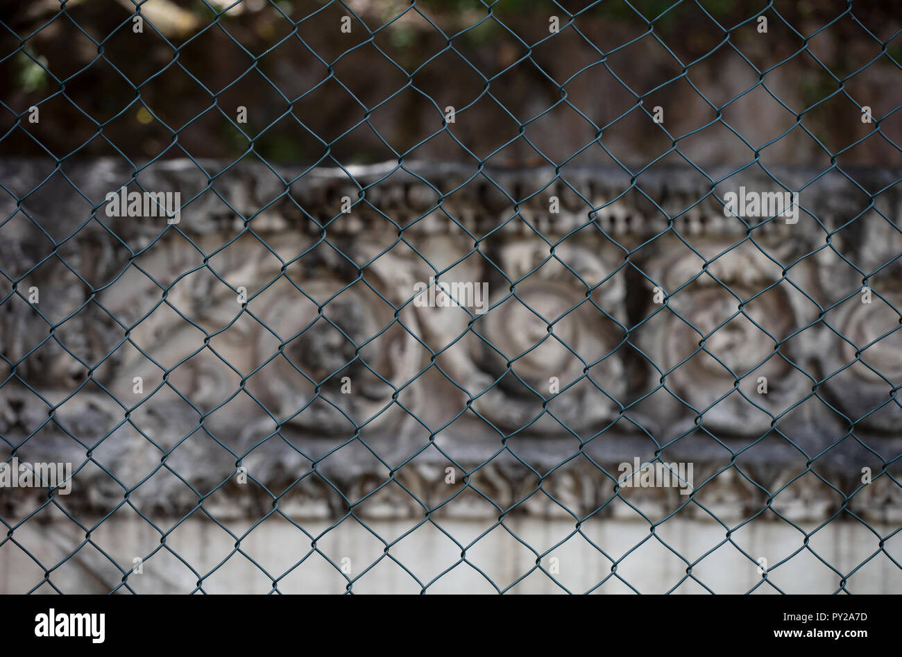 An Roman entablature carved in marble behind a wire fence, locked away ...