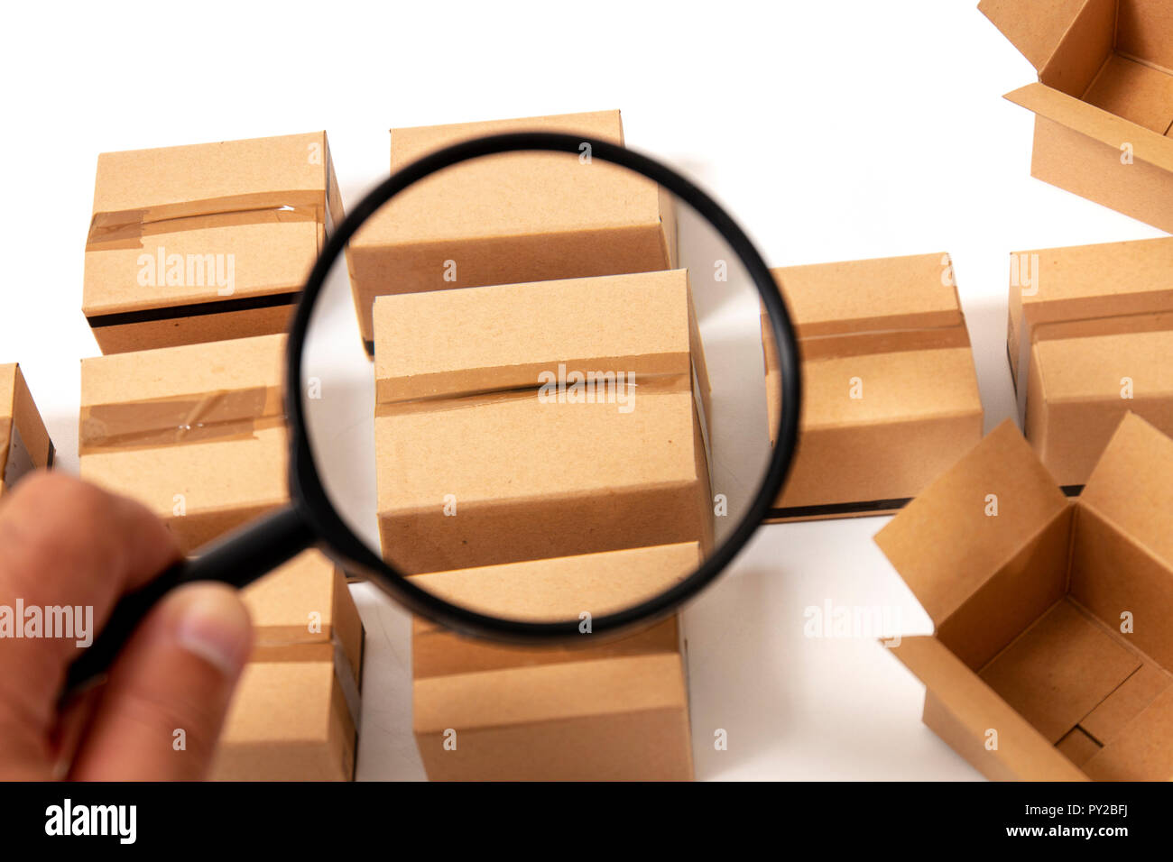 magnifying glass inspecting a cardboard box isolated over a white ...