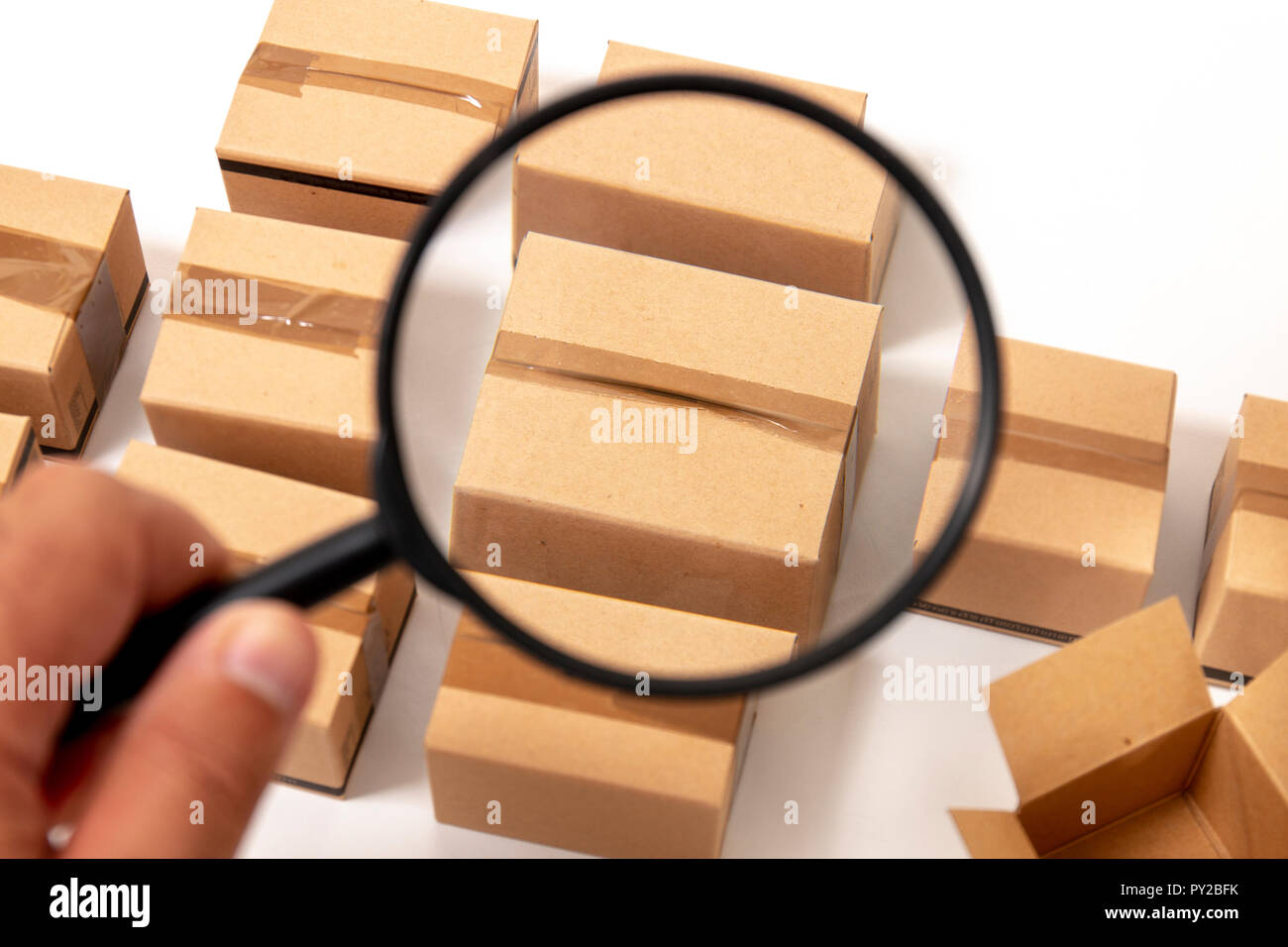 magnifying glass inspecting a cardboard box isolated over a white ...