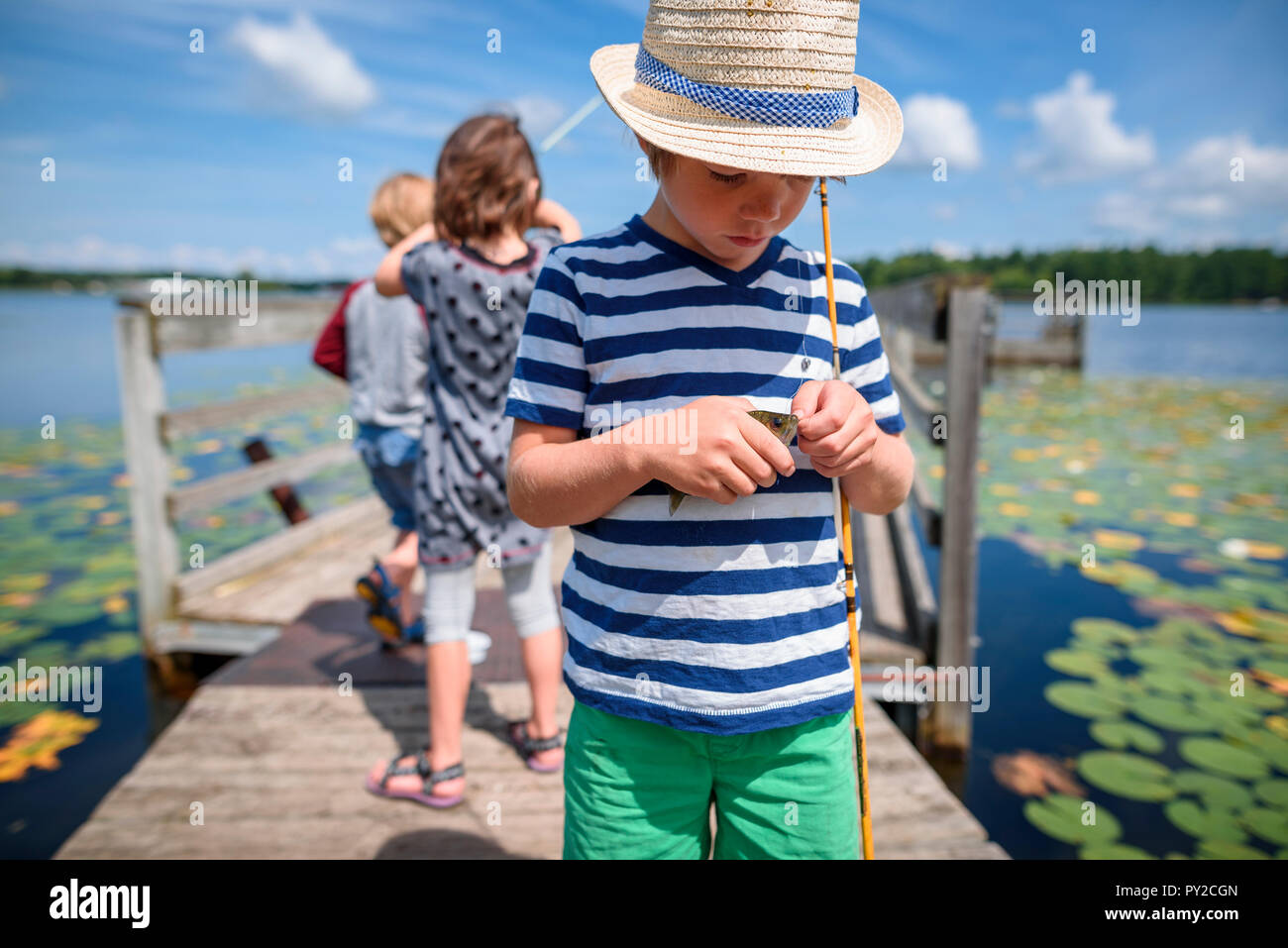 Three children fishing on a dock in the summer, United States Stock ...