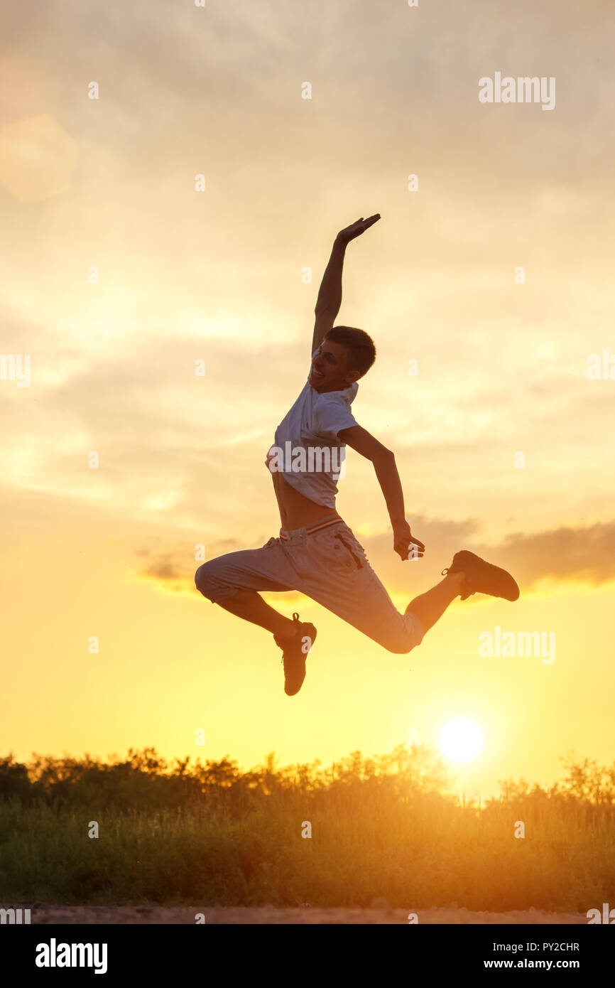 young man jumping up against the sunset sky Stock Photo - Alamy