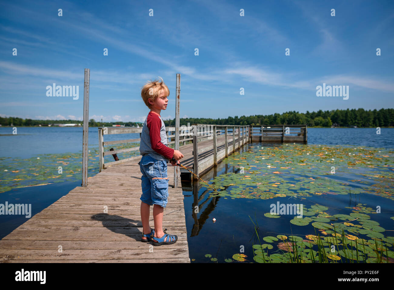Boy standing on a dock fishing, United States Stock Photo - Alamy
