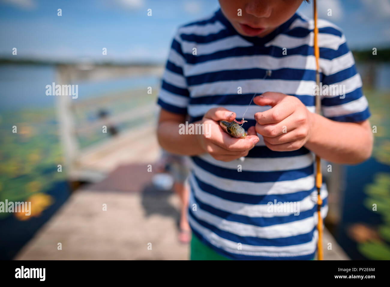 Boy standing on a dock holding a fresh catch of fish, United States ...