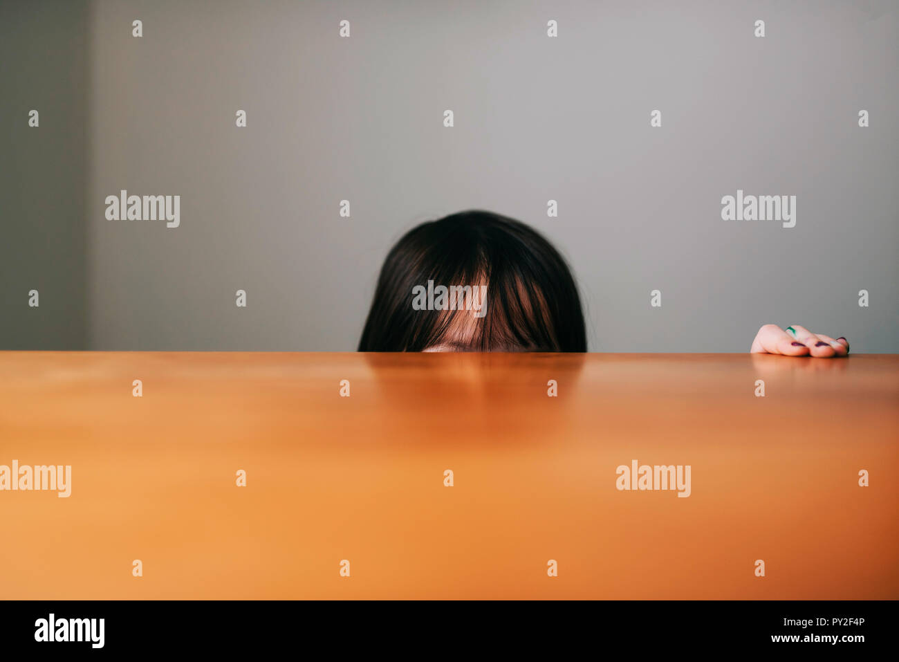 Girl hiding behind a table Stock Photo - Alamy