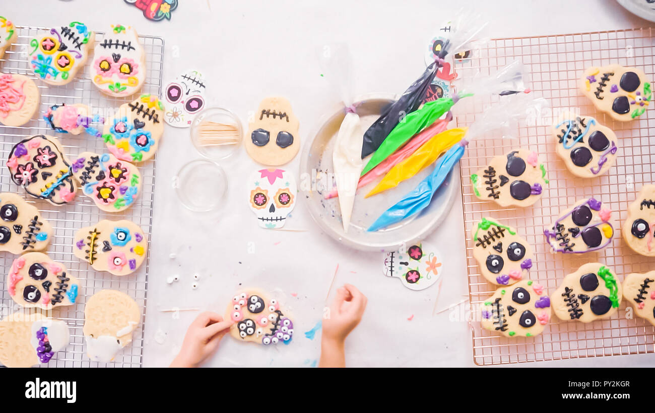 Step by step. Flat lay. Little girl decorating sugar skull cookies with ...