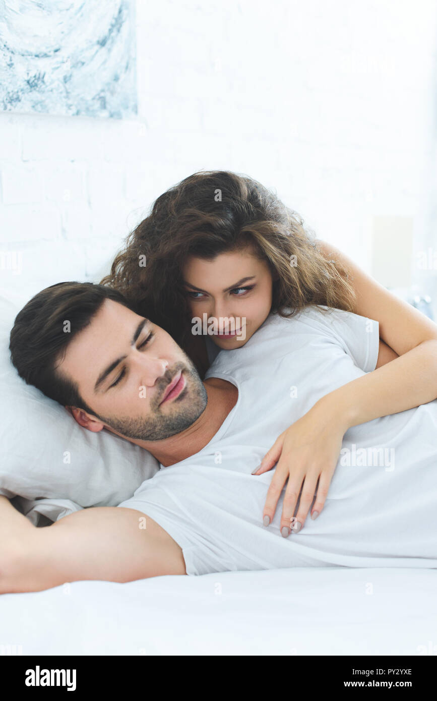 beautiful happy young woman hugging boyfriend sleeping on bed Stock Photo - Alamy