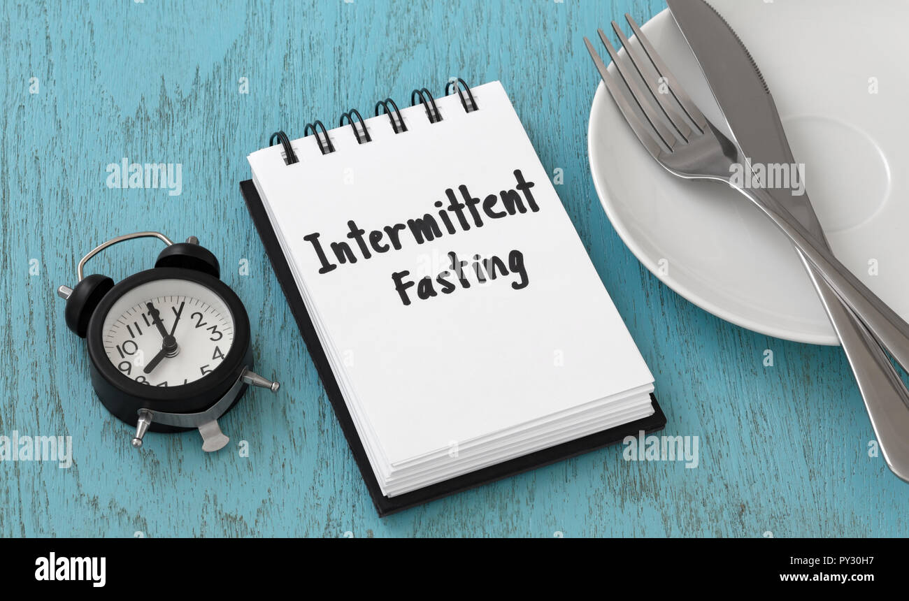 Intermittent fasting word on notepad with clock, fork and knife on ...