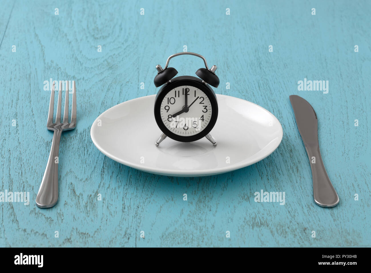 Clock on white plate with fork and knife, intermittent fasting, meal ...