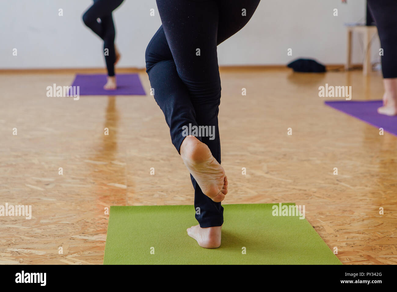 Close up woman's legs doing yoga exercises with teacher on yoga class ...