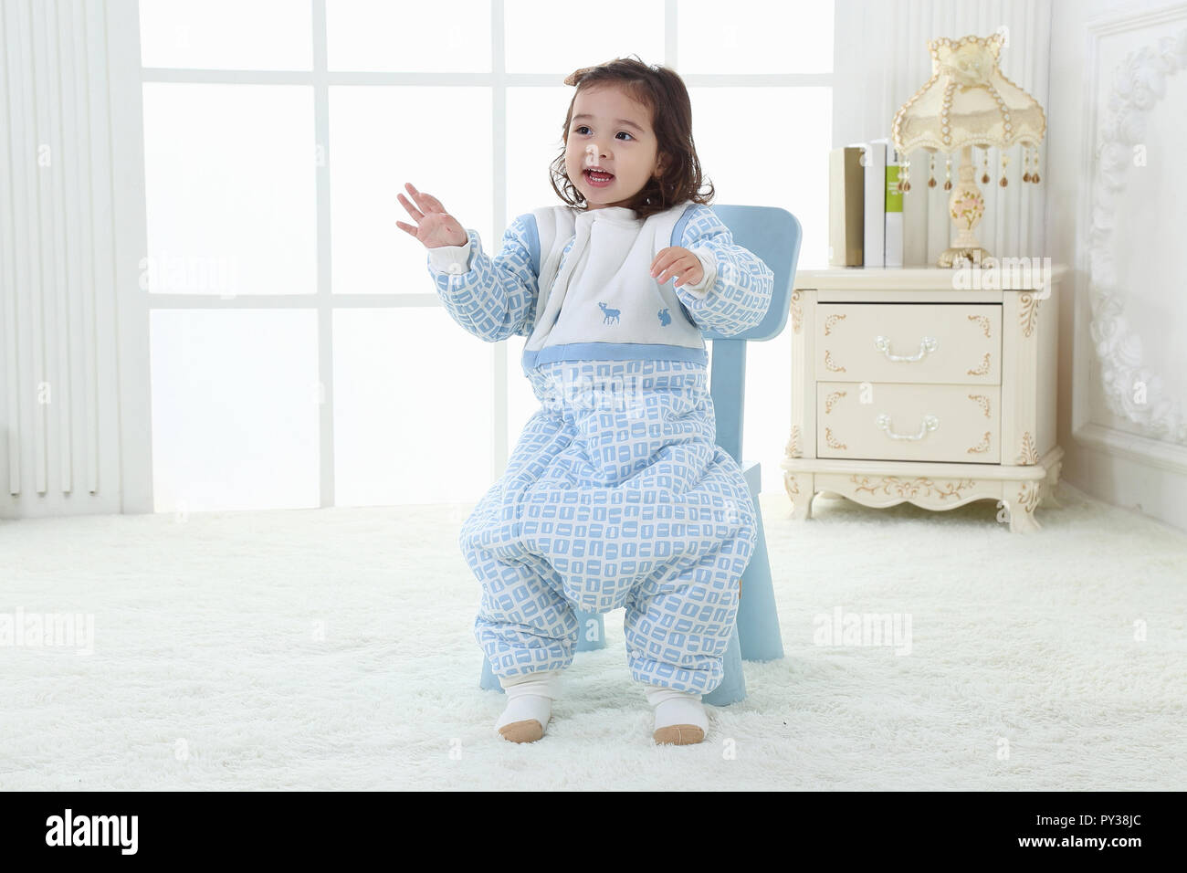 The little girl in a blue dress near a window. Portrait of the little ...