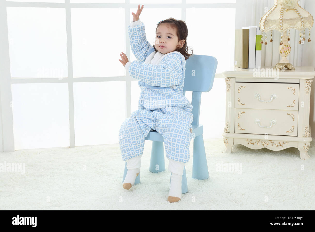 The little girl in a blue dress near a window. Portrait of the little ...