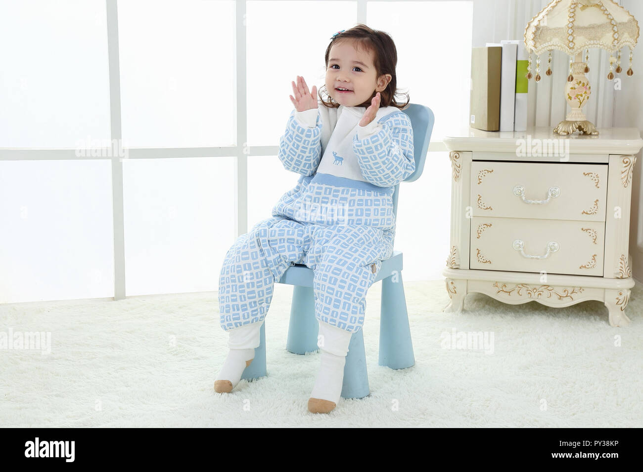 The little girl in a blue dress near a window. Portrait of the little ...
