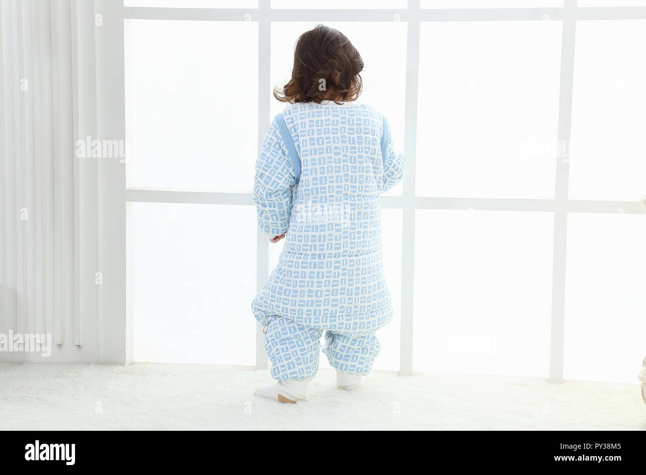 The little girl in a blue dress near a window. Portrait of the little ...