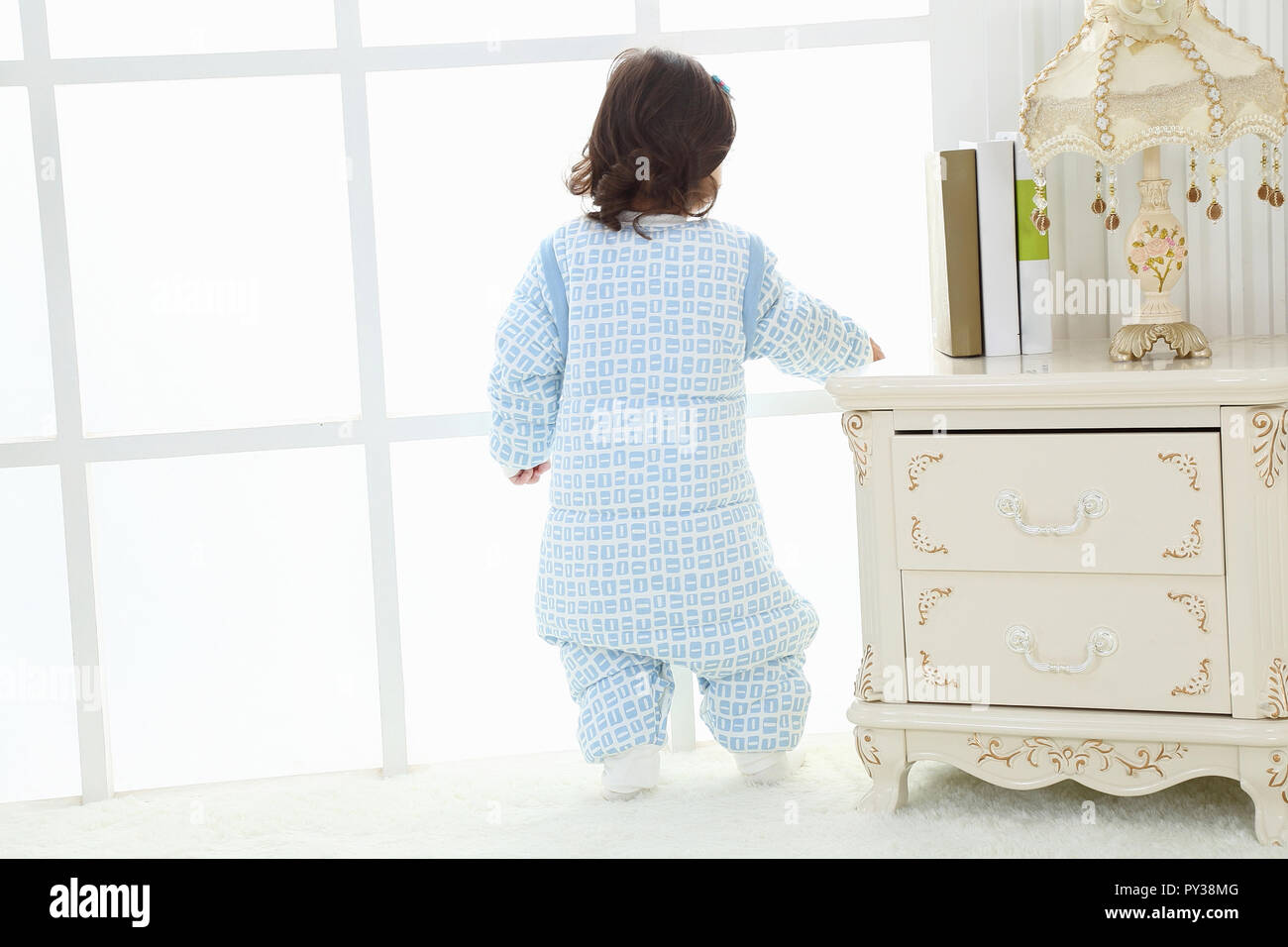 The little girl in a blue dress near a window. Portrait of the little ...