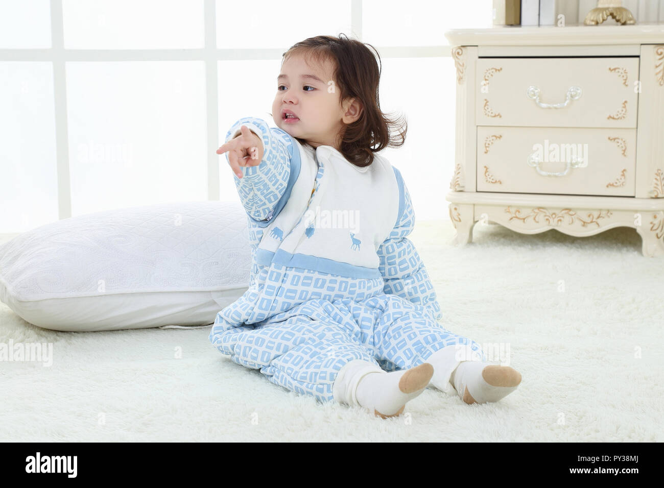 The little girl in a blue dress near a window. Portrait of the little ...