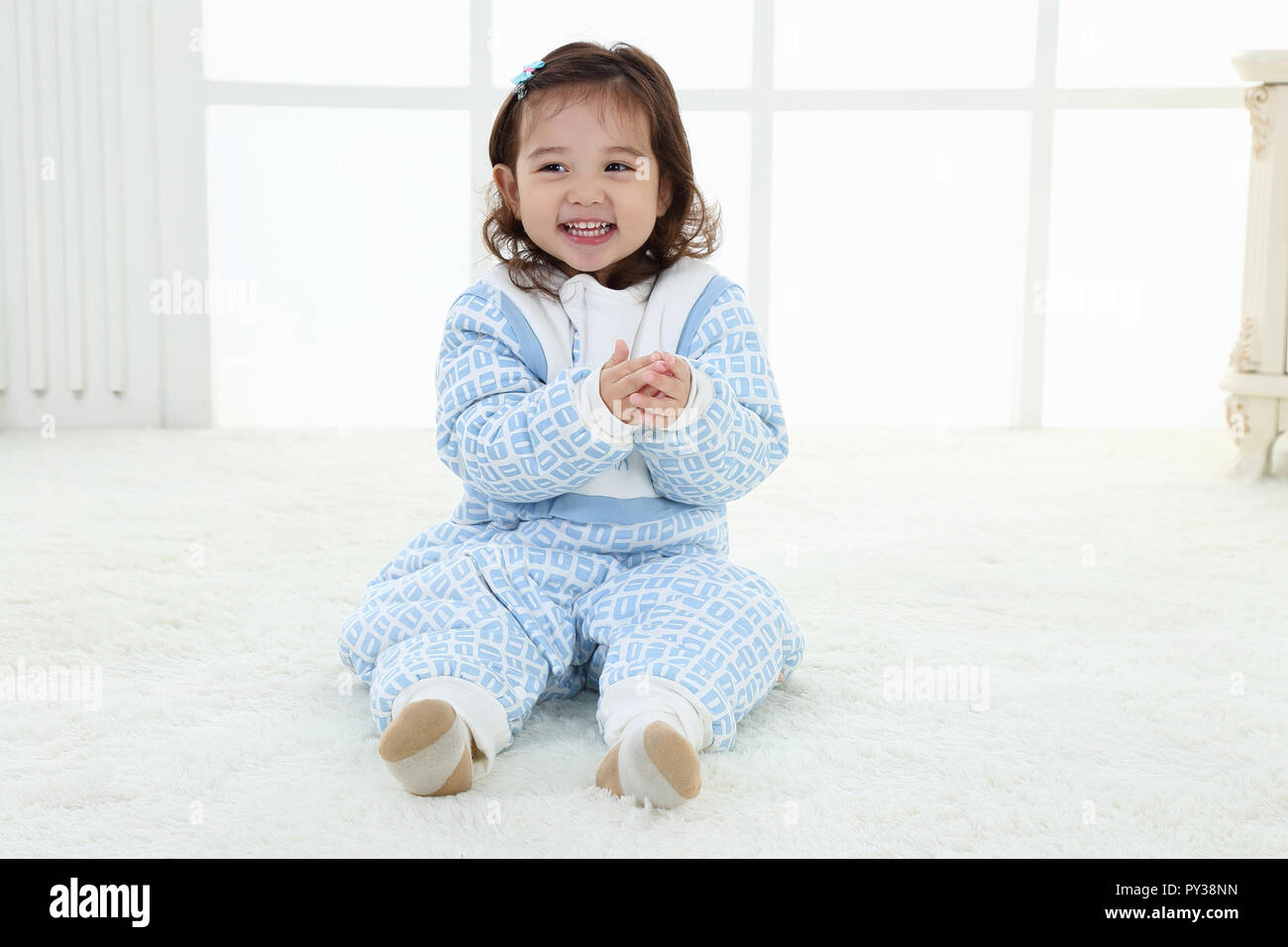The little girl in a blue dress near a window. Portrait of the little ...