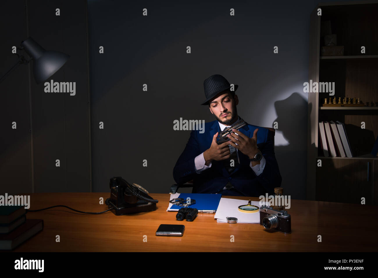 Detective sitting in dark room in vintage concept Stock Photo - Alamy