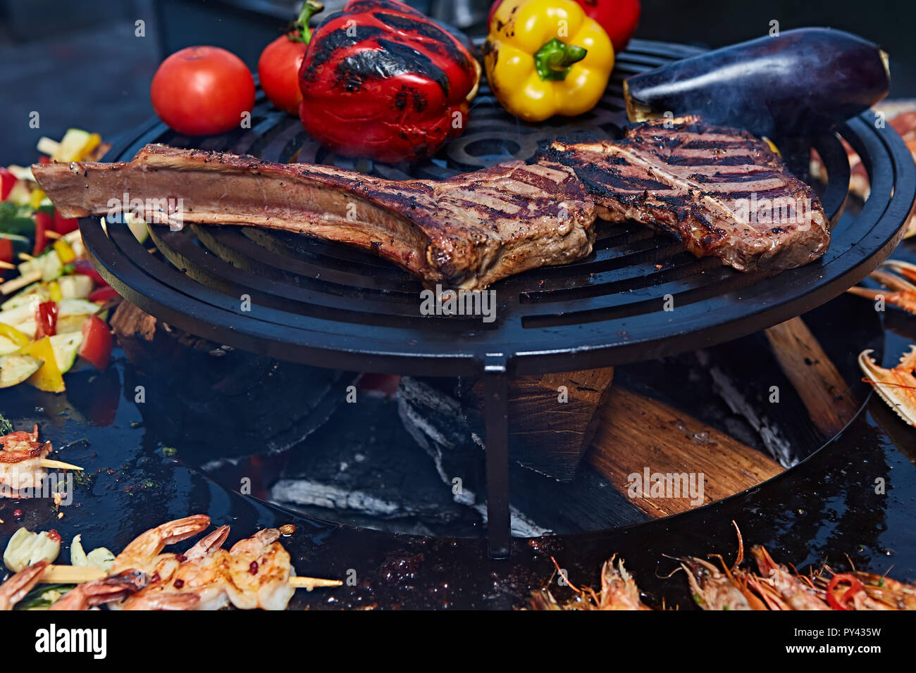 Tomahawk rib beef steak and T-bone on hot black grill Stock Photo - Alamy