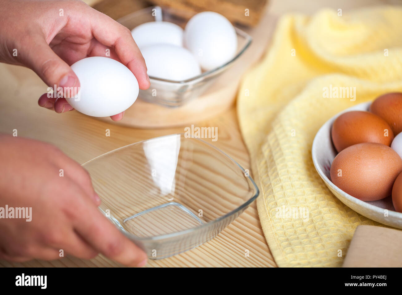 Woman hands breaking an egg to separate egg white and yolks, egg shells at the background Stock ...