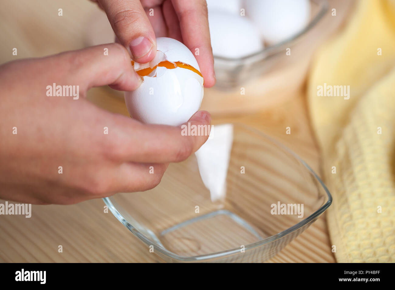 Woman hands breaking an egg to separate egg white and yolks, egg shells ...