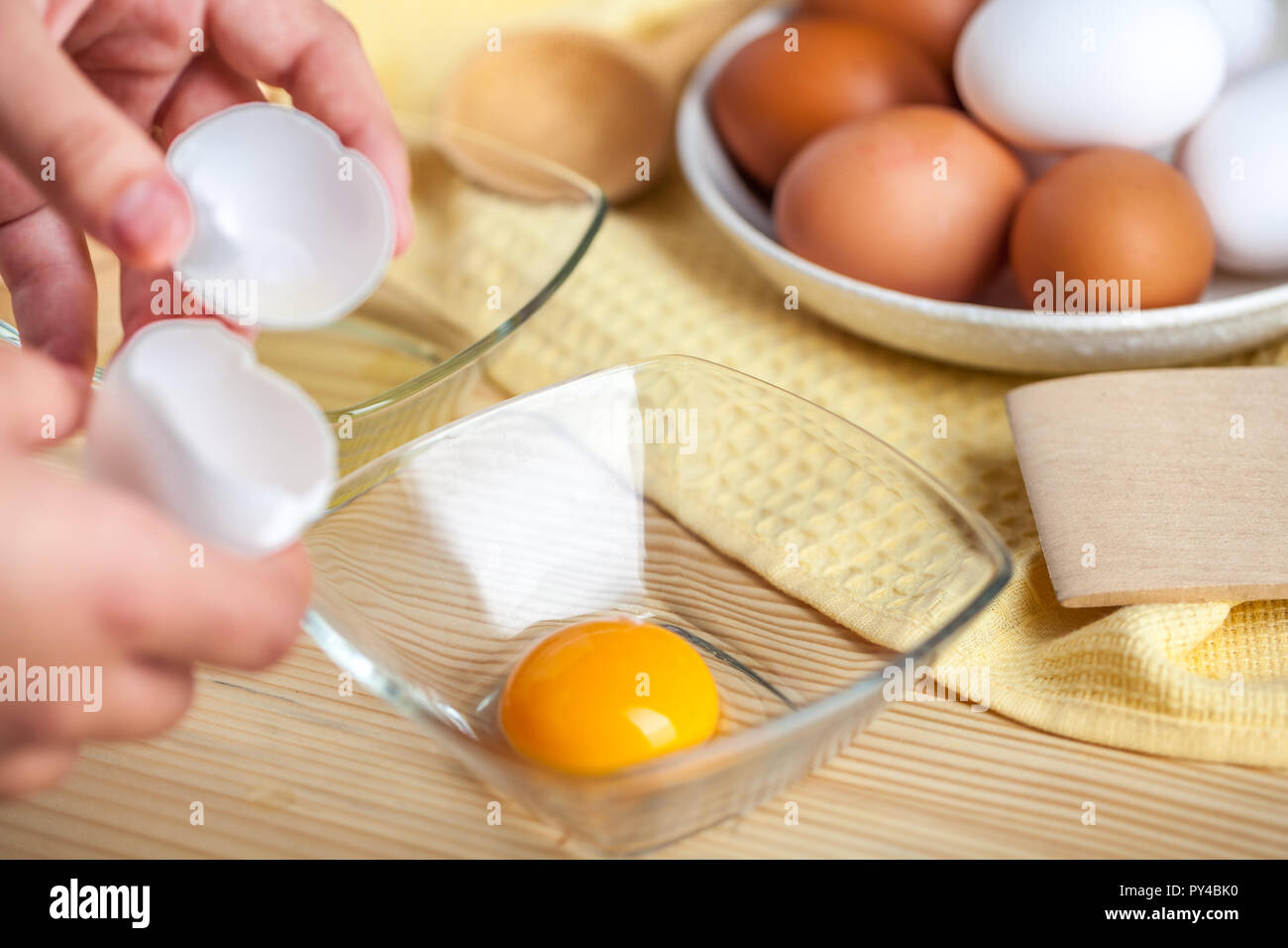 Woman hands breaking an egg to separate egg white and yolks, egg shells at the background Stock ...