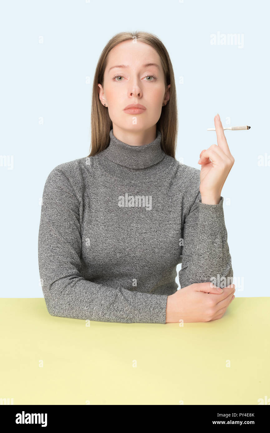 The young woman smoking cigarette while sitting at table at studio ...