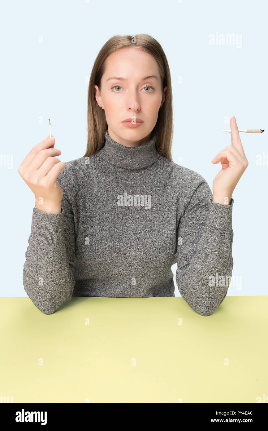 The young woman smoking cigarette while sitting at table at studio ...